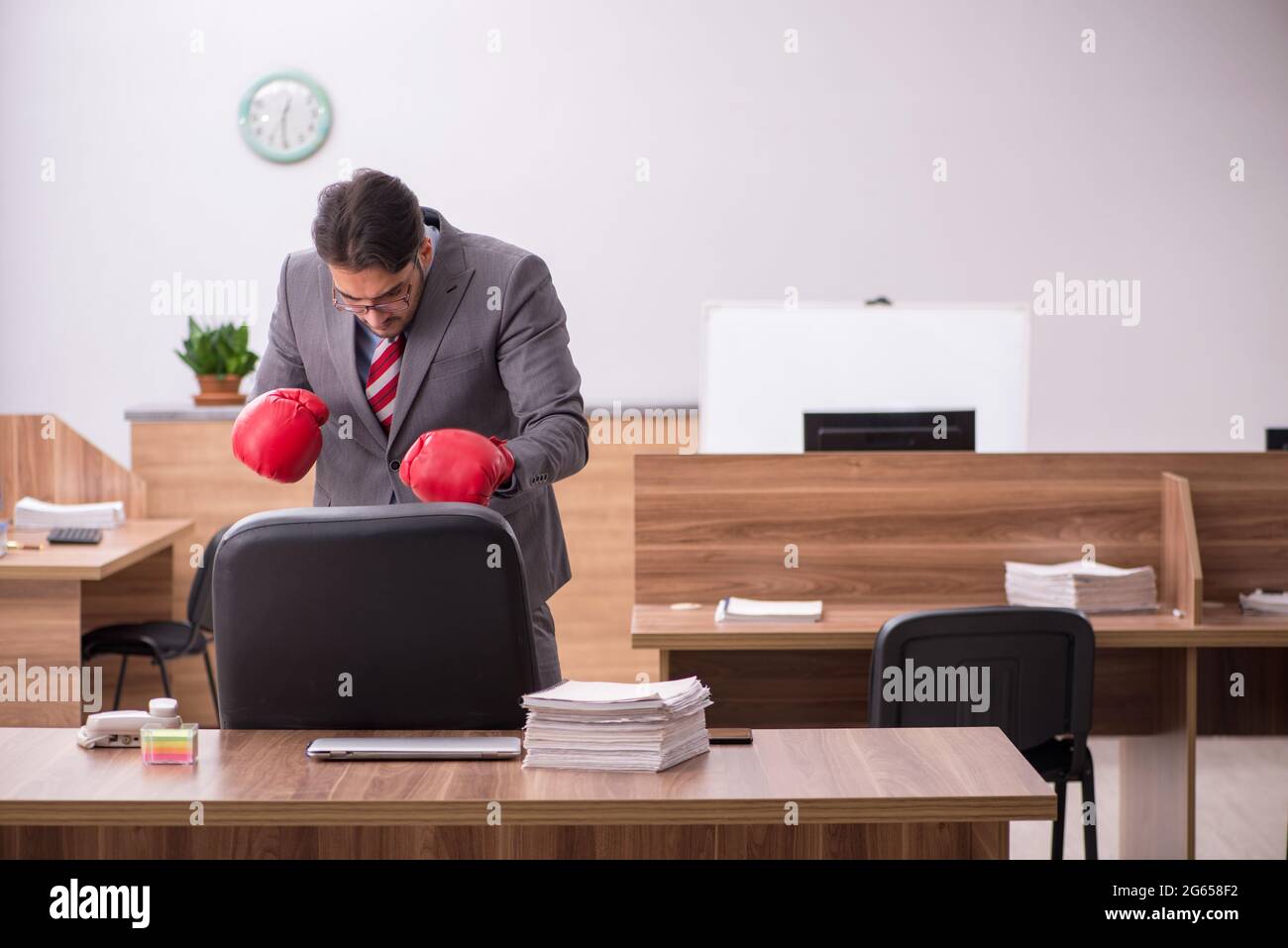 Young businessman employee wearing boxing gloves at workplace Stock ...