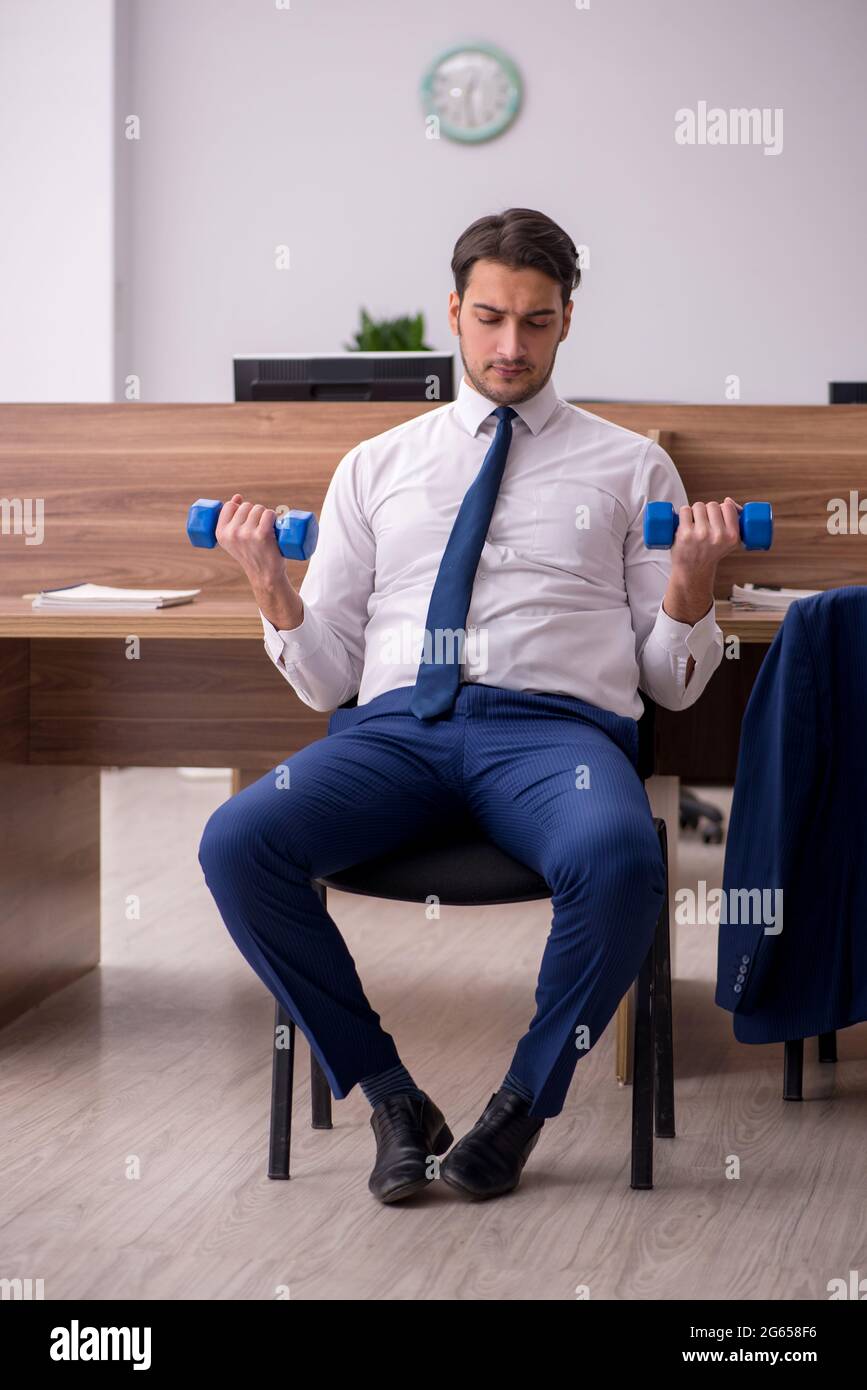 Young male employee doing sport exercises in the office Stock Photo - Alamy