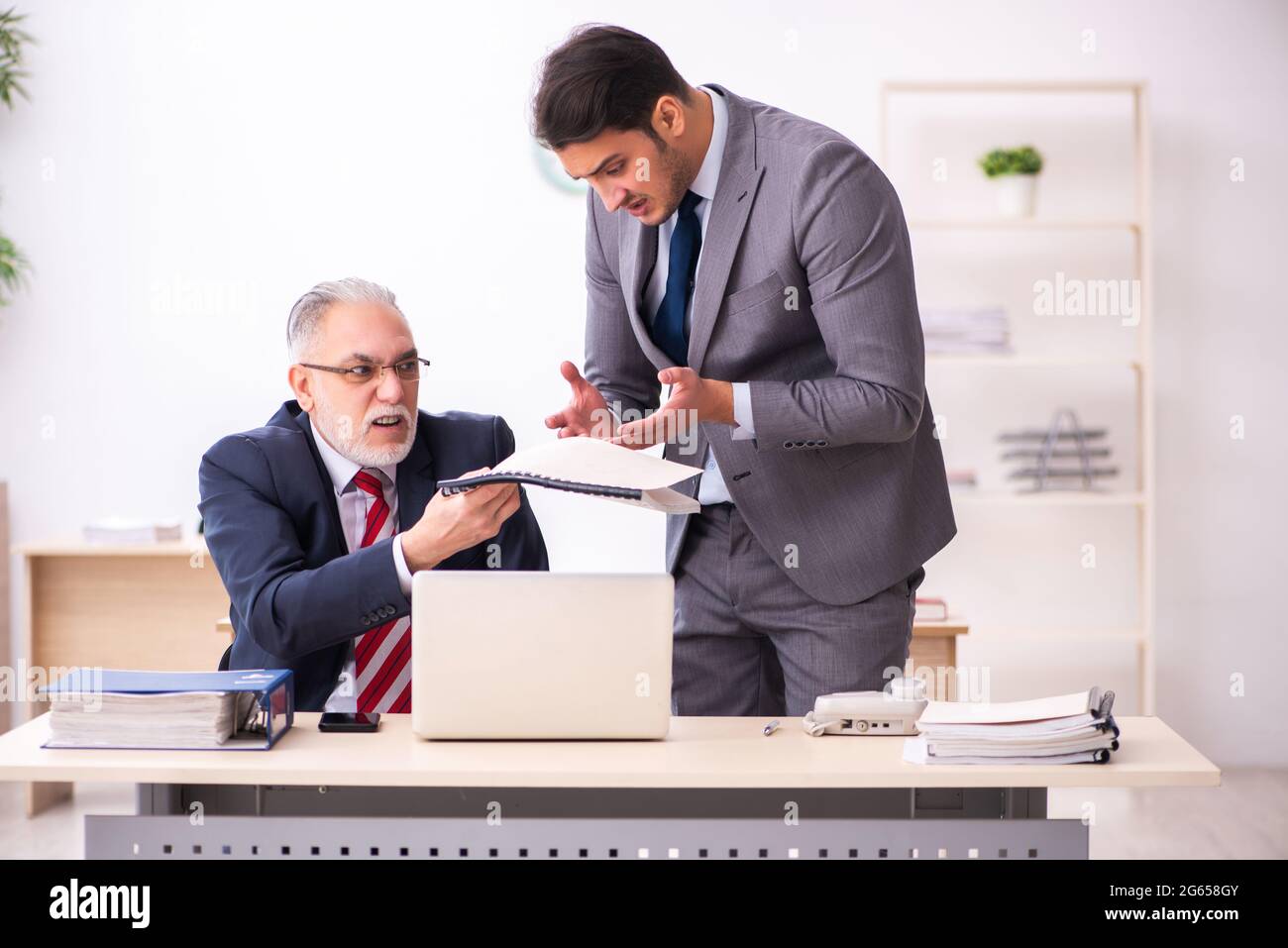 Old boss and young employee working at workplace Stock Photo - Alamy