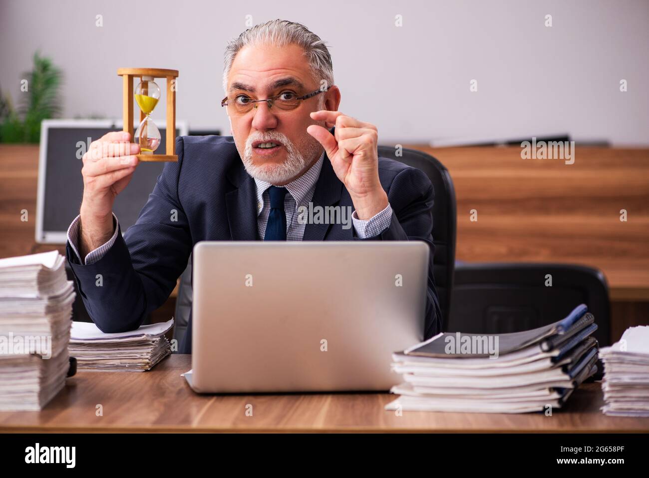 Old businessman employee in time management concept Stock Photo - Alamy