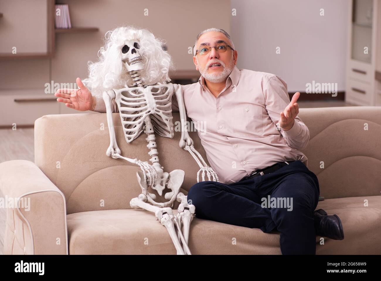 Old man sitting on the sofa with the female skeleton in undying love ...