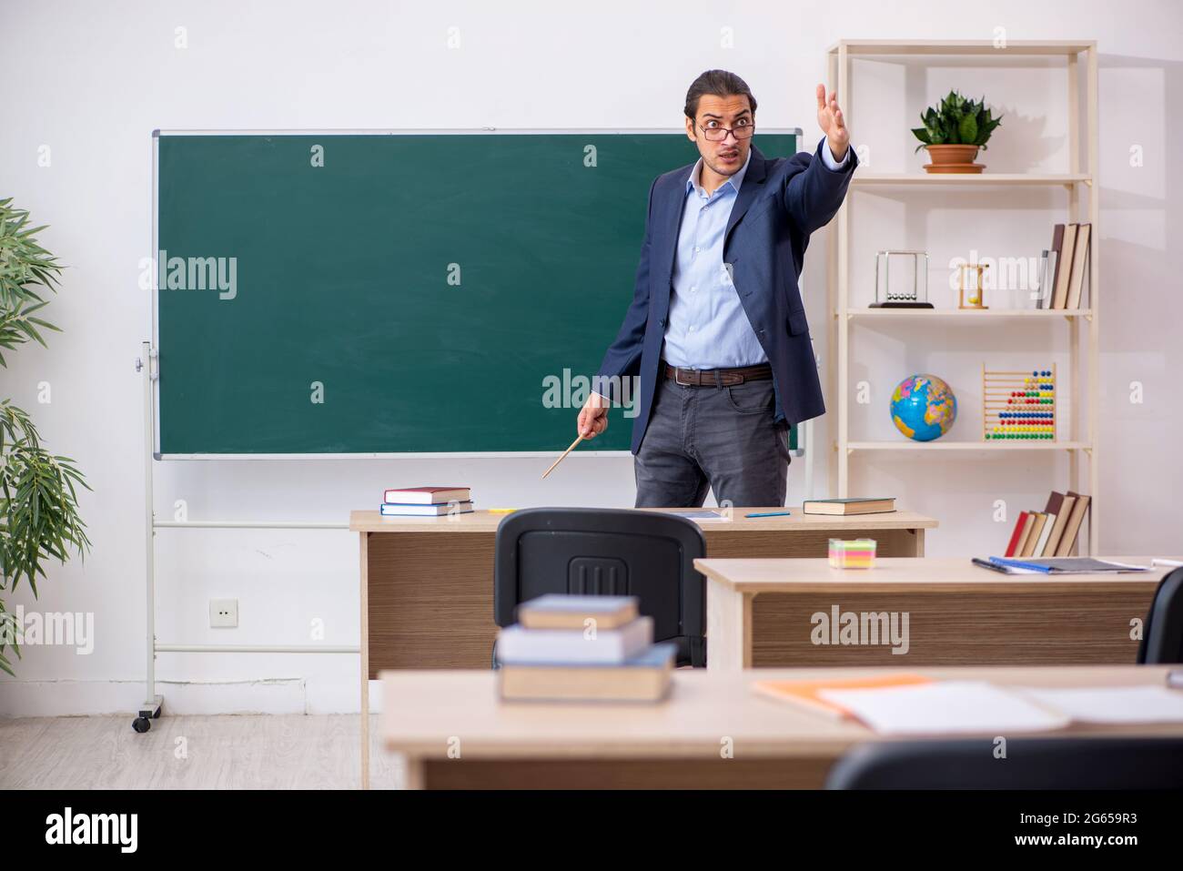 Young teacher in front of green board Stock Photo - Alamy