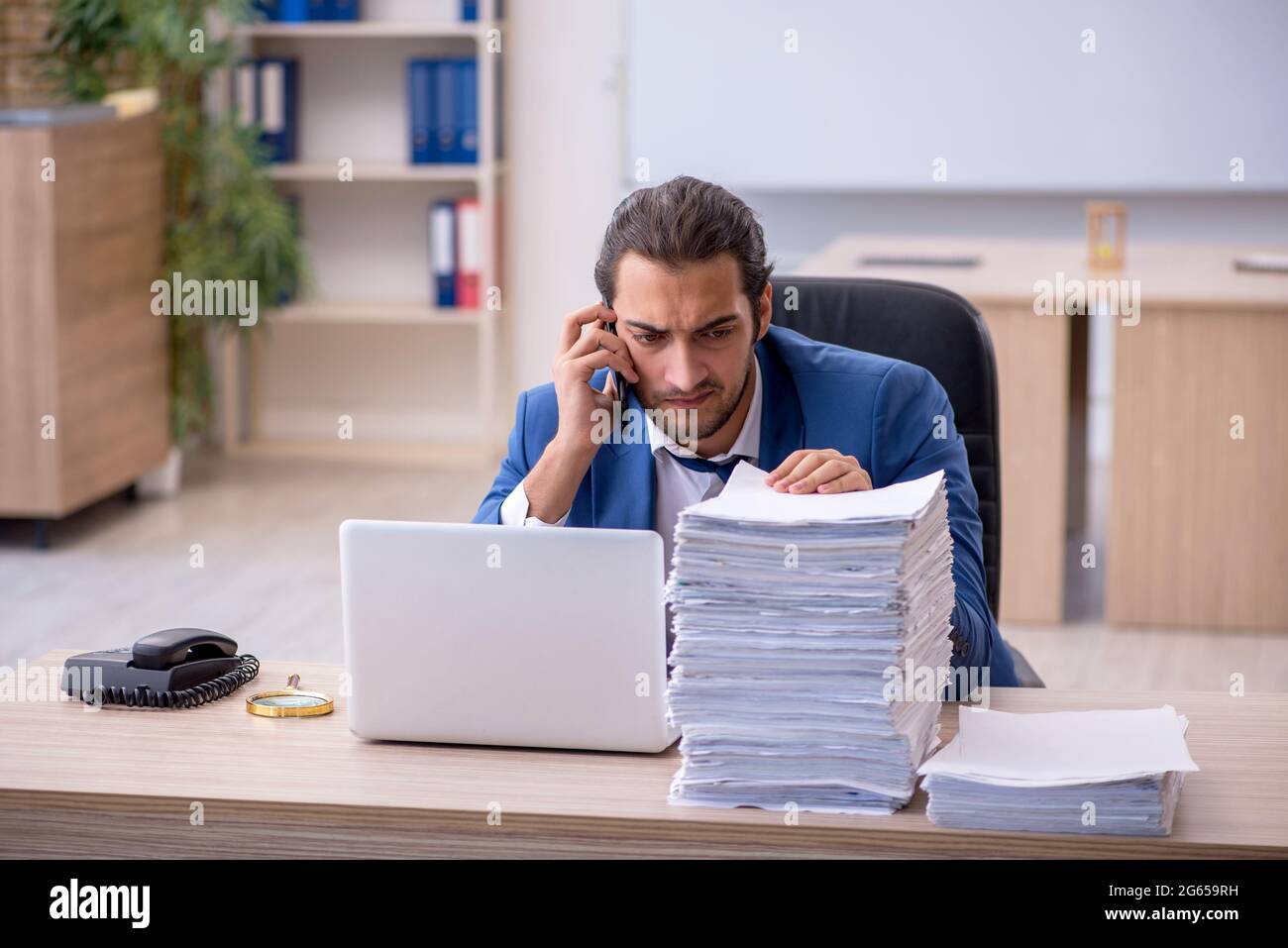 Young employee and too much work in the office Stock Photo - Alamy