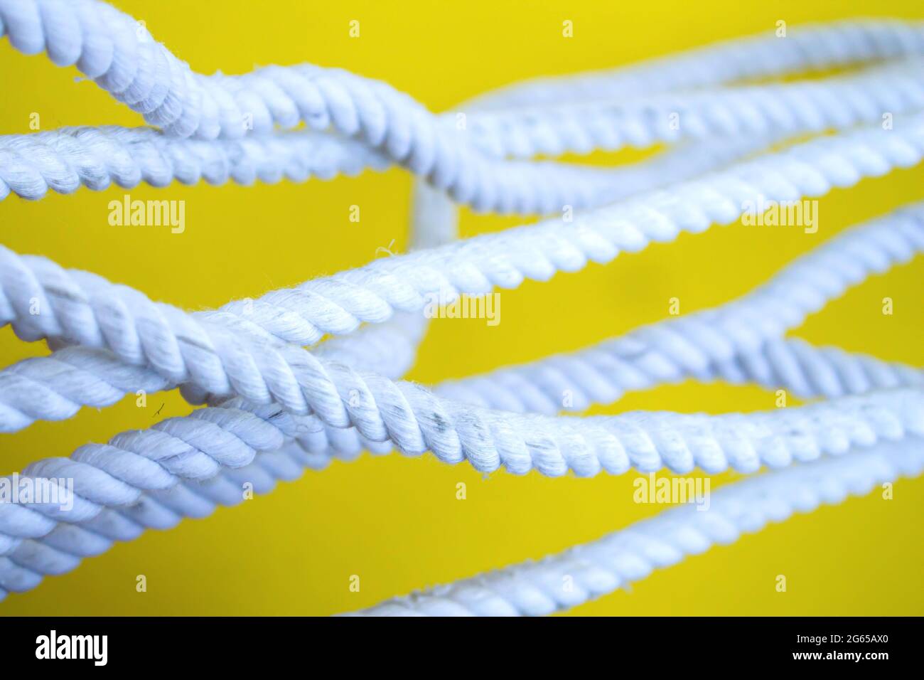 White rope on a yellow background. Rope close-up. The rope sections are ...