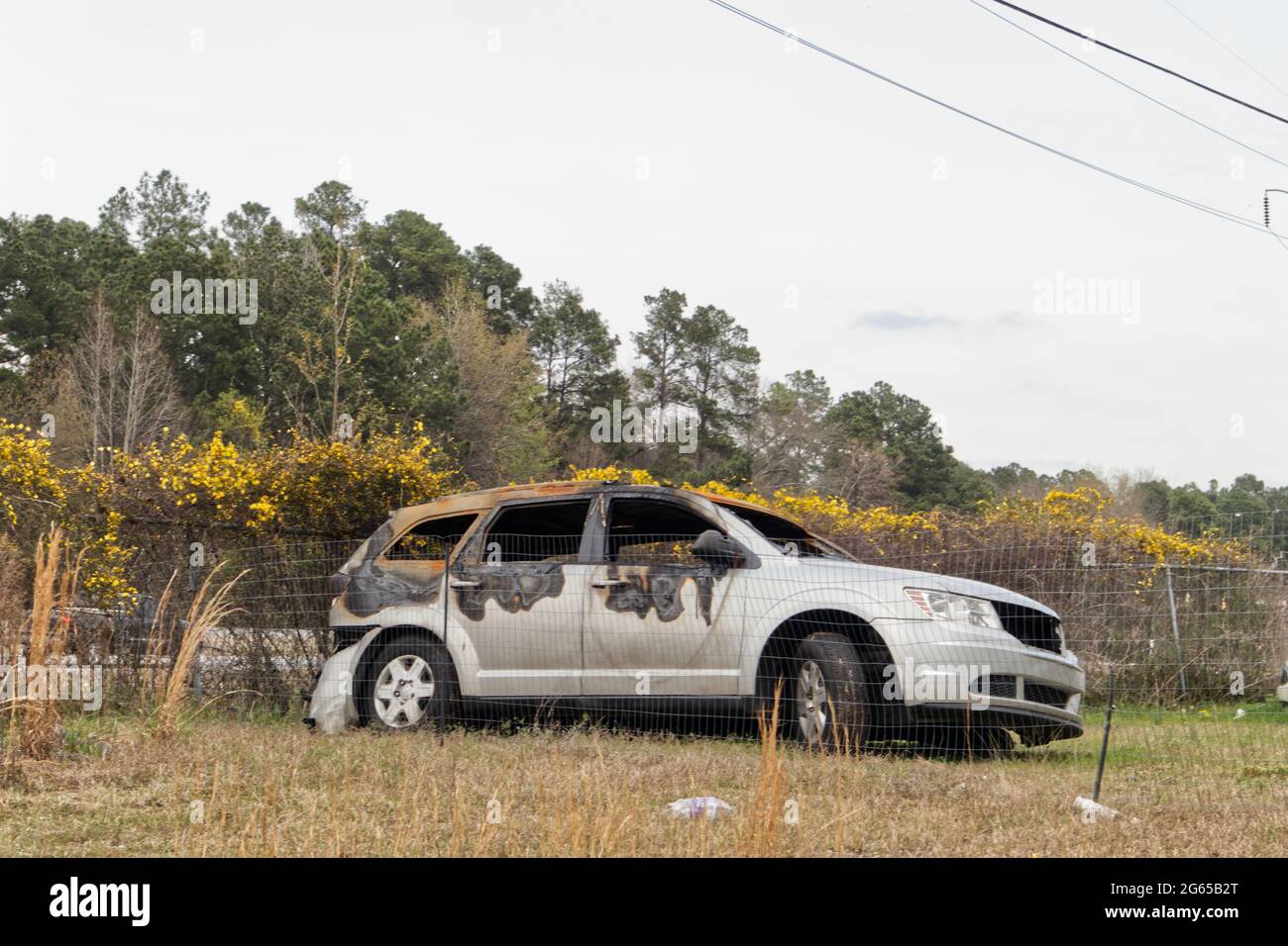 Augusta, Ga USA - 03 17 21: A burned minivan from a fire behind a wire ...