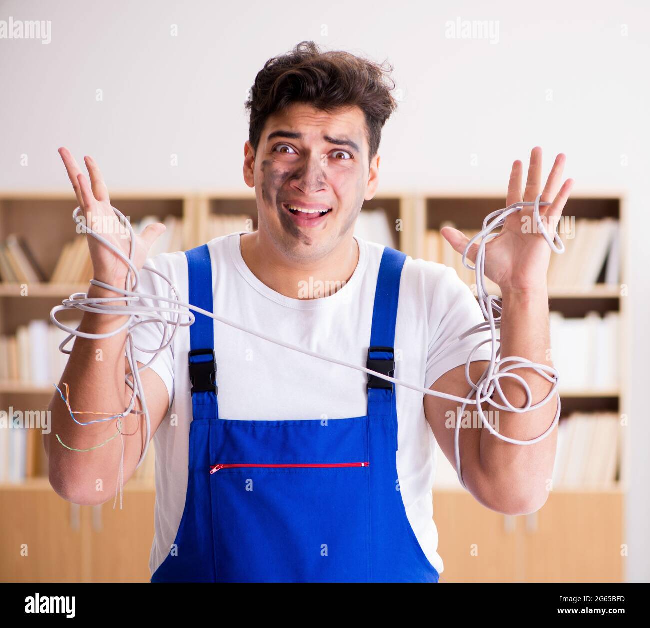 The funny young electrician tangled in cables Stock Photo - Alamy