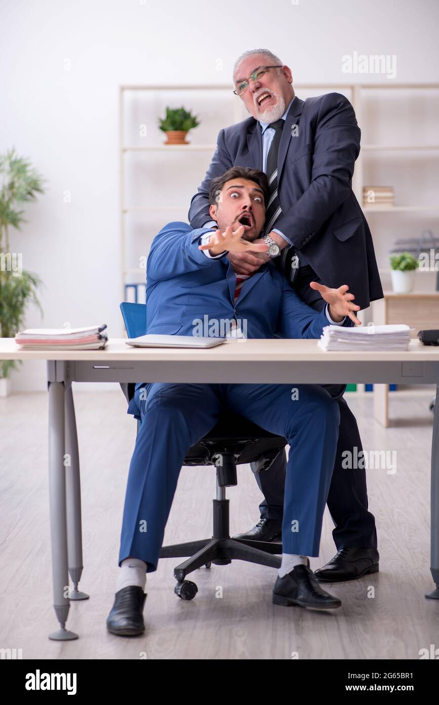 Old boss and young employee in bullying concept Stock Photo - Alamy
