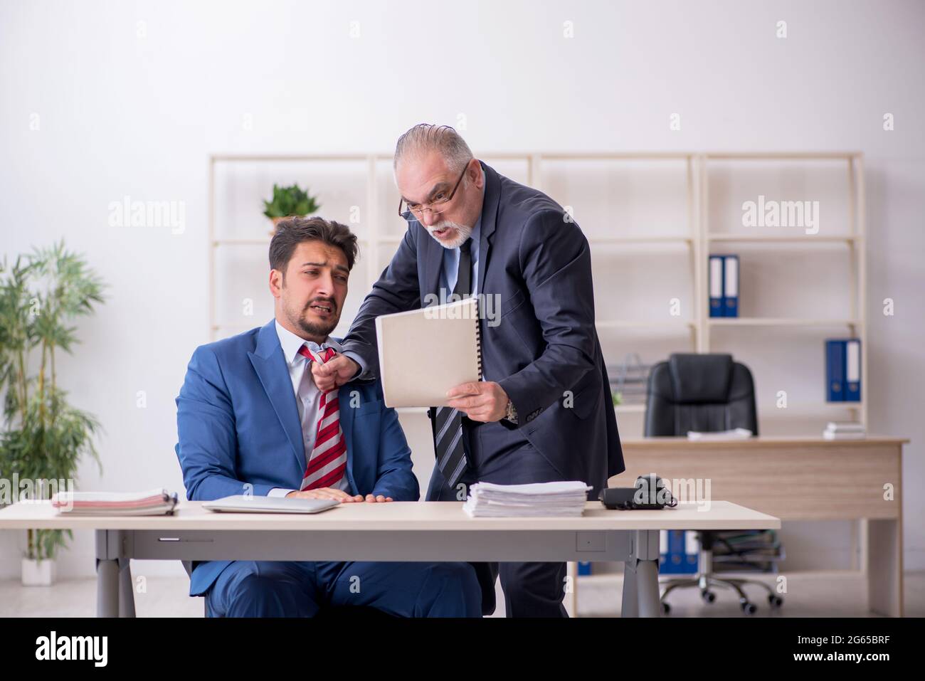 Old boss and young employee in bullying concept Stock Photo - Alamy