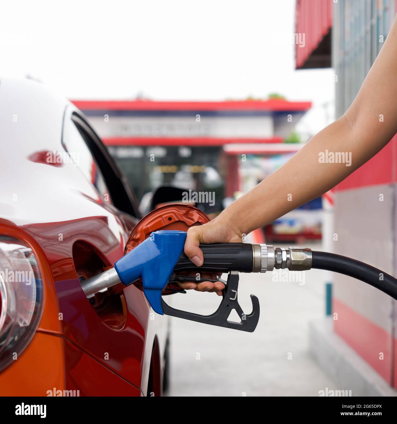 Gas station worker's hand holding blue benzene gas pump, filling up red ...