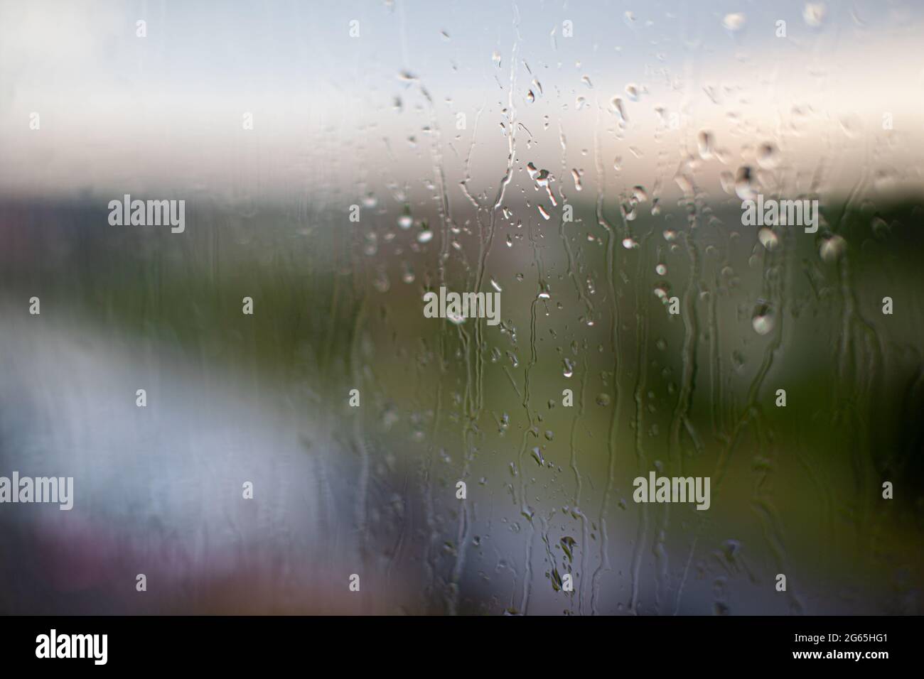 Rainy day through the window on cloudy grey sky and city buildings ...