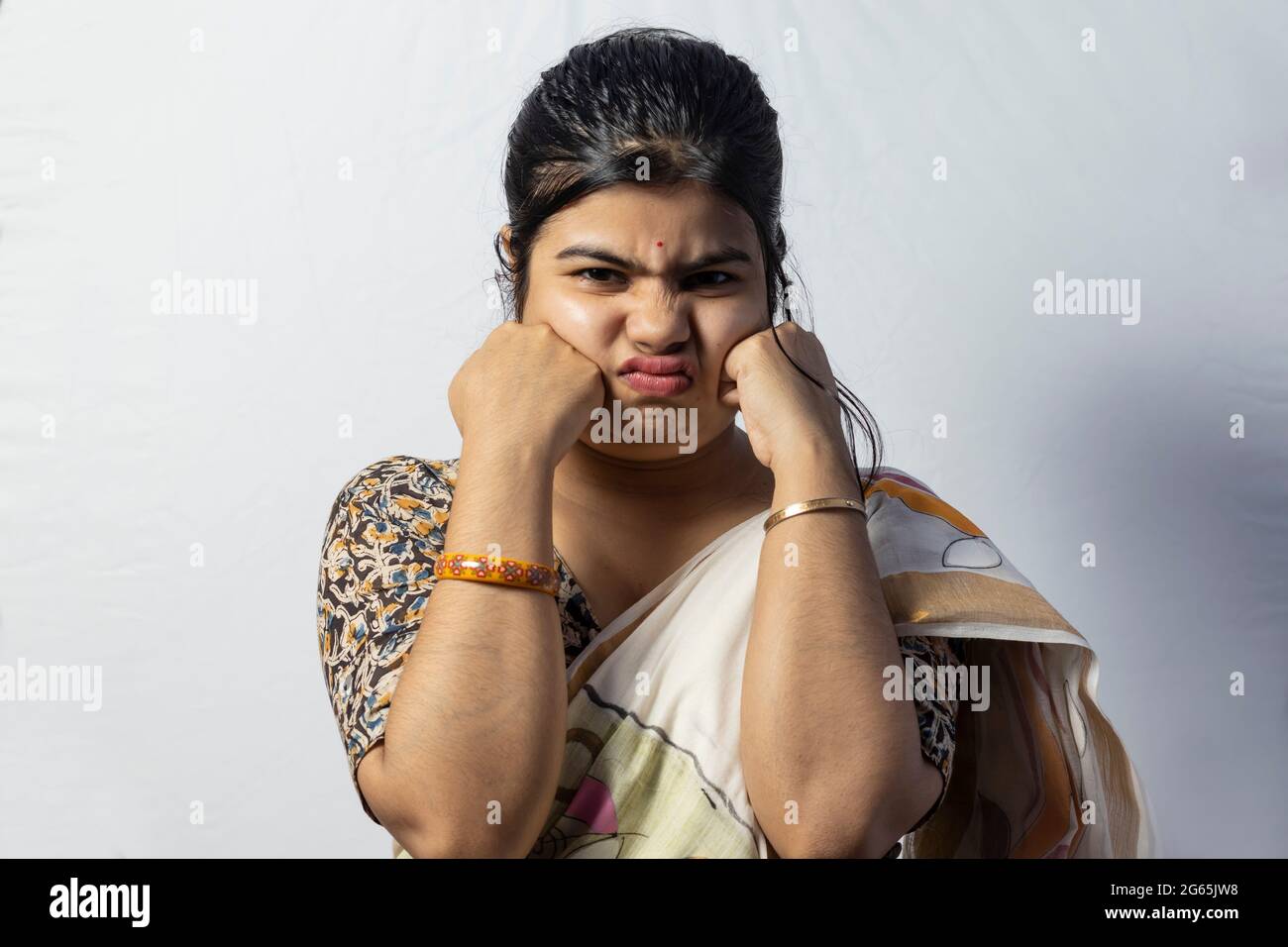 Isolated on white background an Indian female in saree shows angry face ...