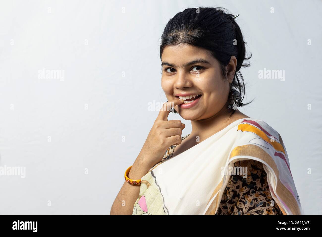 Isolated On White Background An Indian Female In Saree Biting Nails With Smile On White