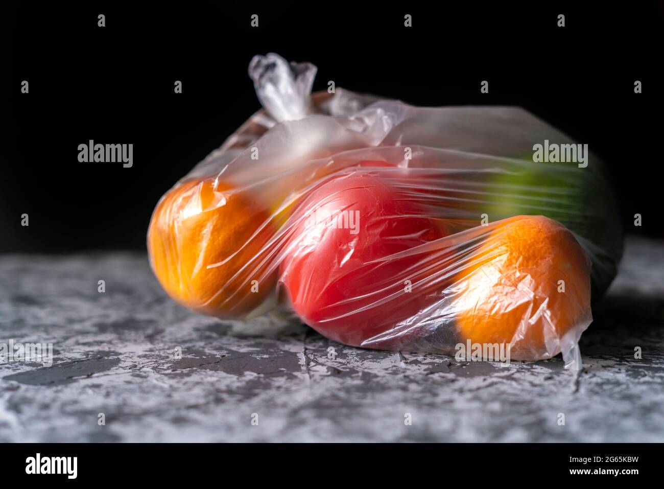 damaged spoiled fruits in a bag in a dark room, plastic container harm ...