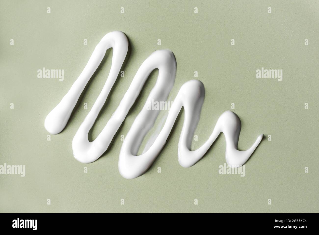 Cosmetic cream wave on green background, top view. White swatch of skin ...