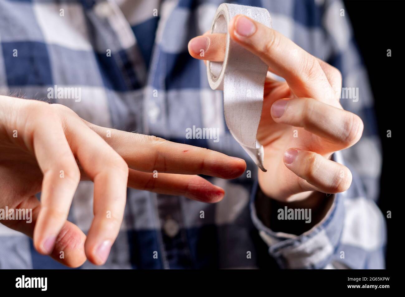 young man giving first aid to himself by putting a patch tape on the ...