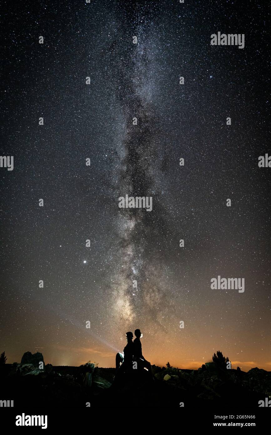 Milky way and two people silhouette with beam light Stock Photo - Alamy