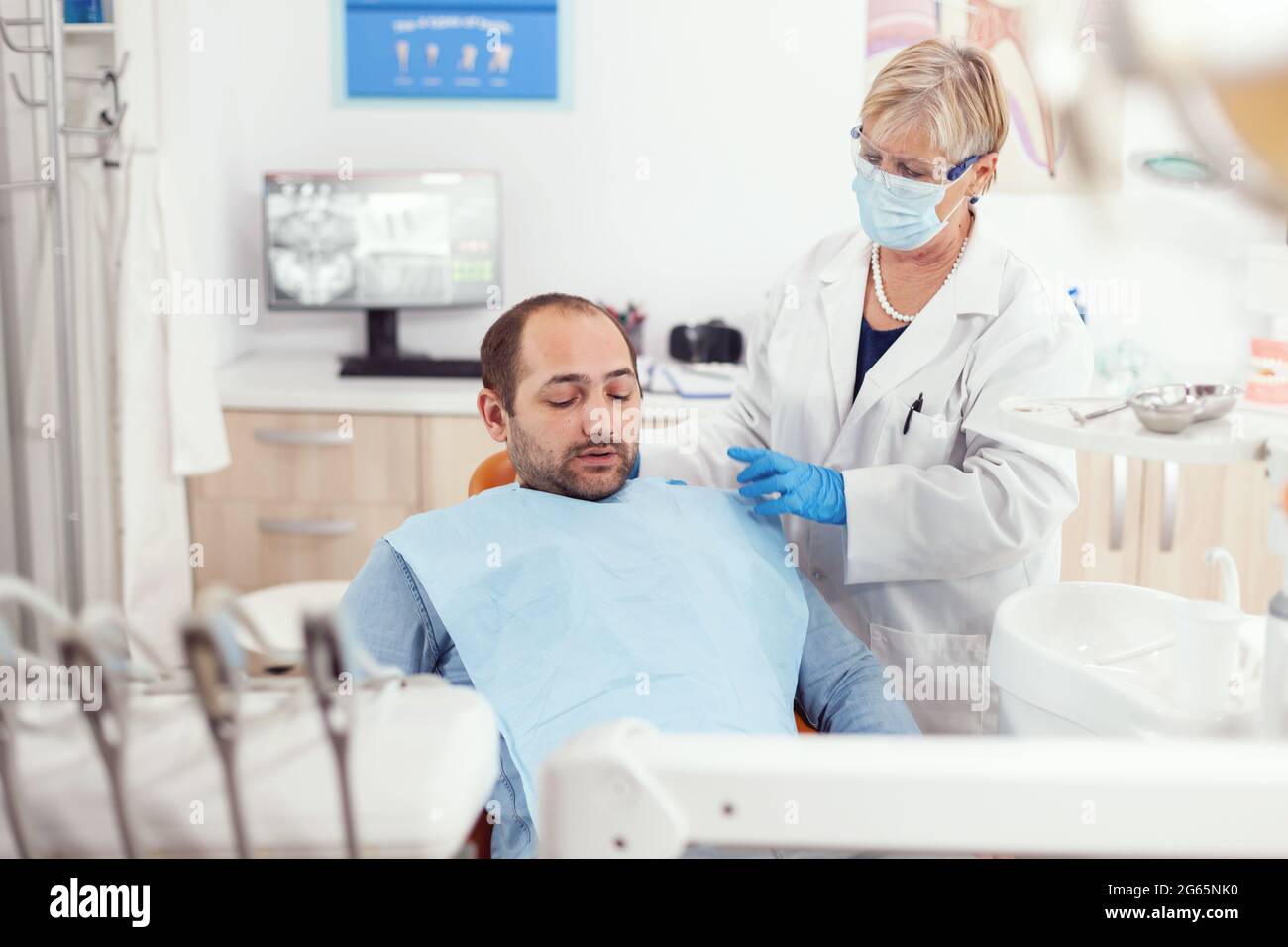 Senior stomatologist helping patient to stand up after dental surgery ...