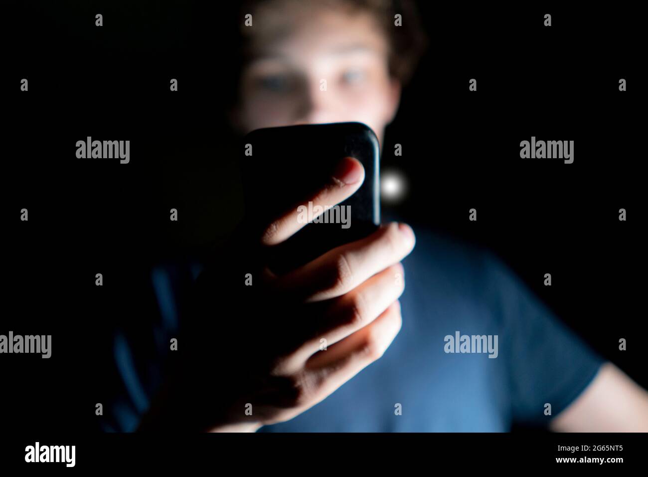 young attractive man use mobile phone late at night in a dark room ...