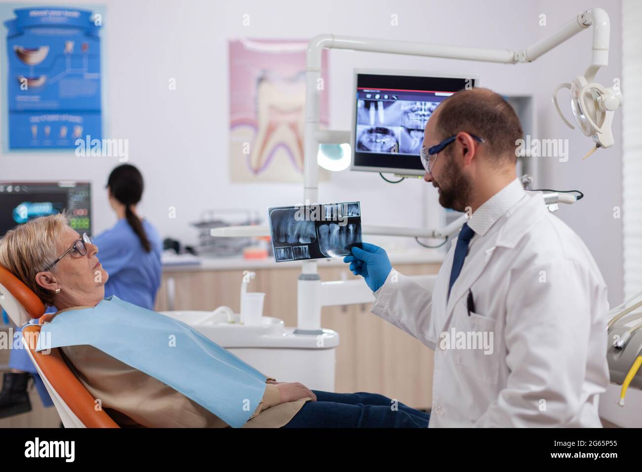 Dentist assistant giving doctor radiography of senior woman waiting ...