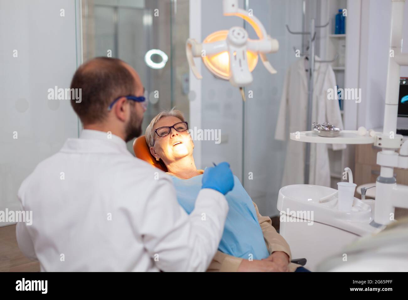 Denstis in cabinet repairing senior patient tooth in dental clinic ...