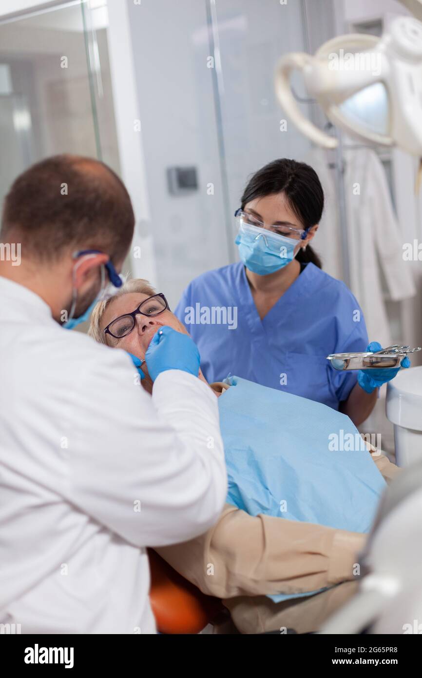 Dentist with assistant install implant in patient mouthin modern clinic ...