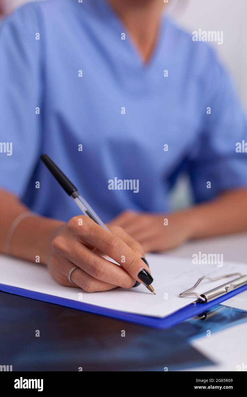 Close up of nurse writing patient diagnosis on clipboard in hospital ...