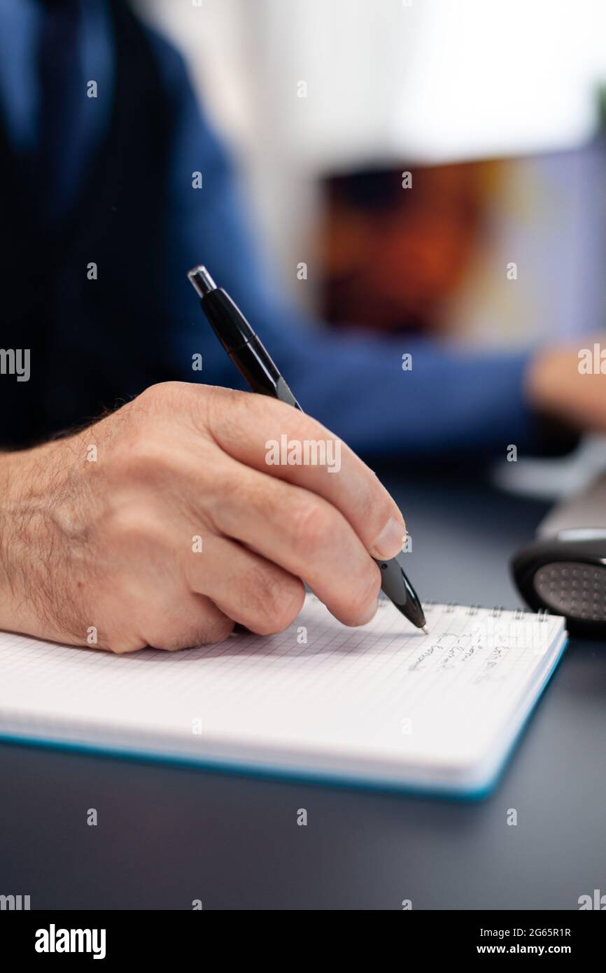 Close up of man taking notes on notebook while working from home ...