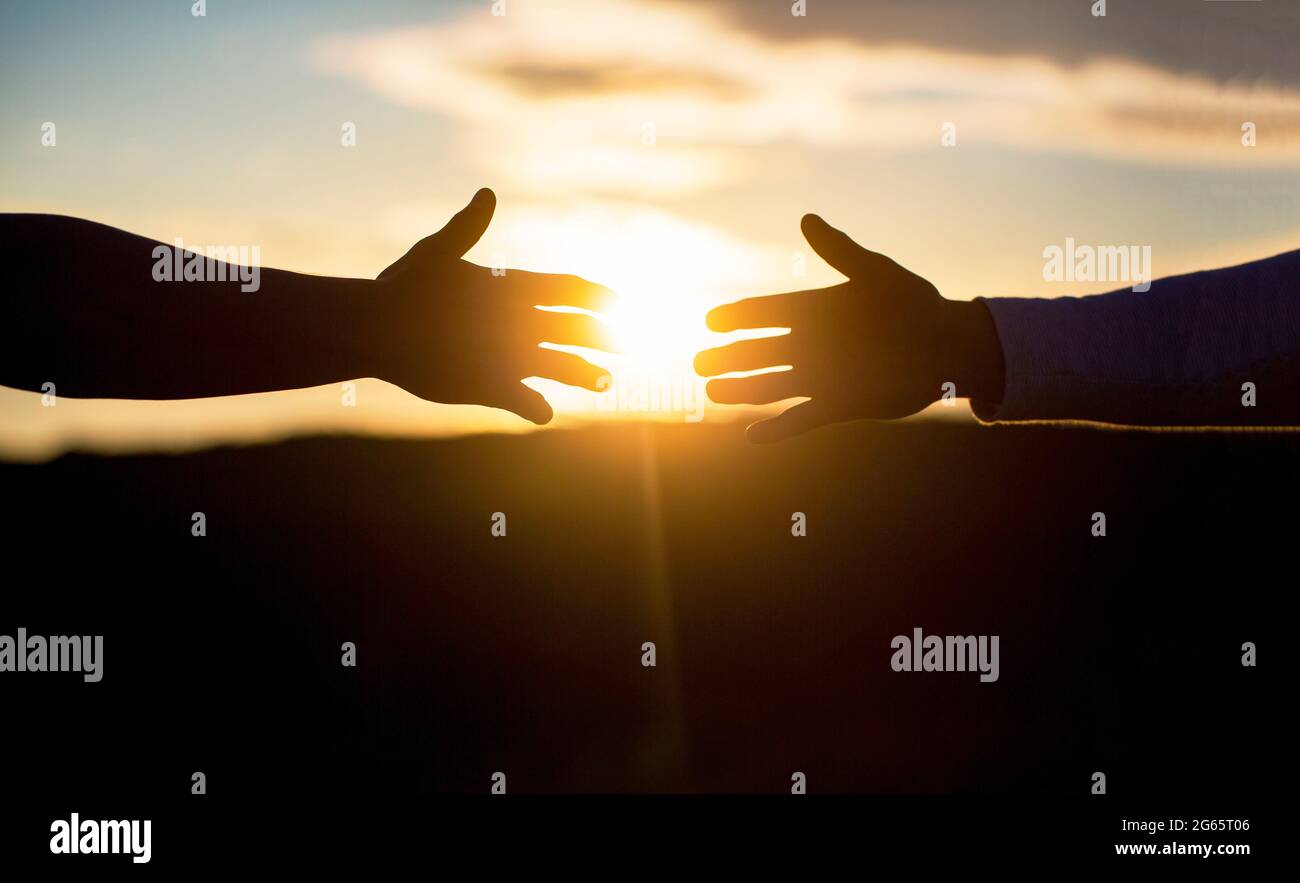 Two hands silhouette on sky background, connection or help concept. Outstretched hands ...
