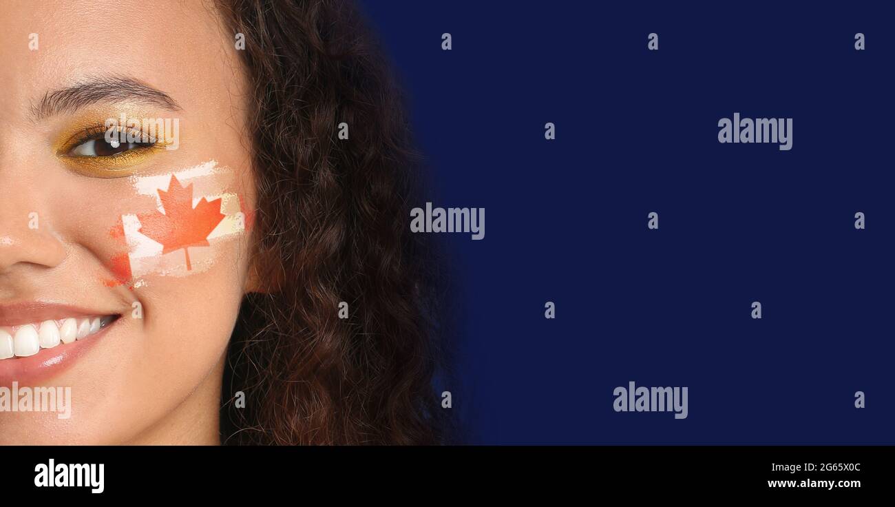 Young woman with face in colors of Canadian flag on blue background ...