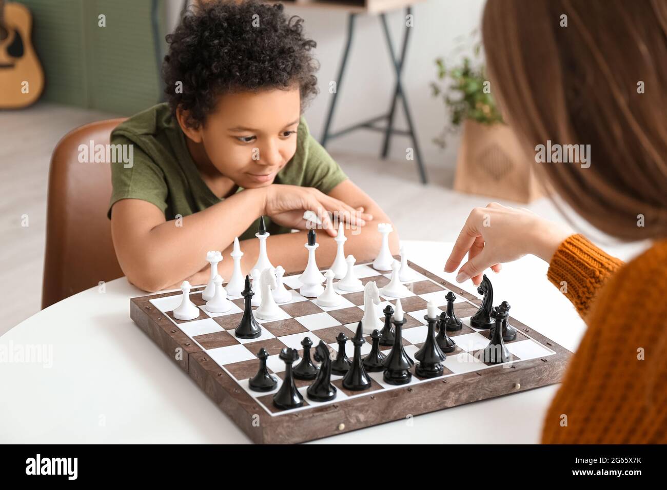 Cute African-American boy and his mother playing chess at home Stock ...