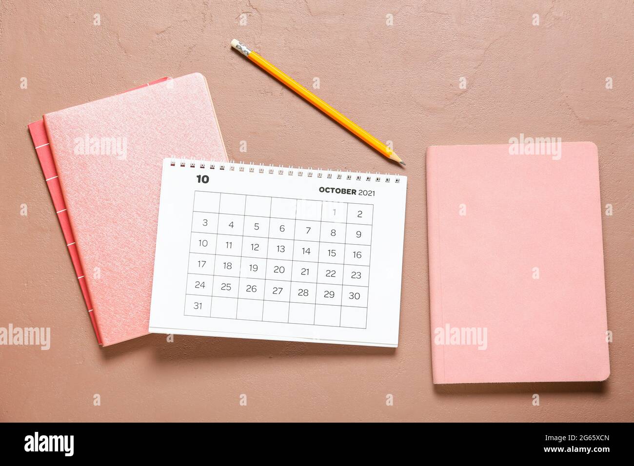 Flip paper calendar, notebooks and pencil on color background Stock ...