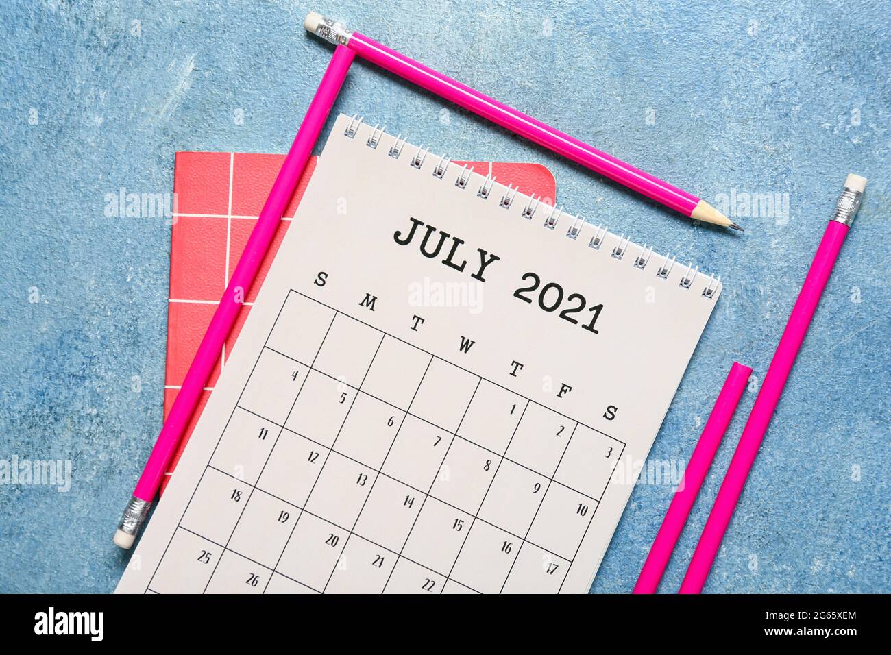 Flip paper calendar and pencils on color background Stock Photo - Alamy