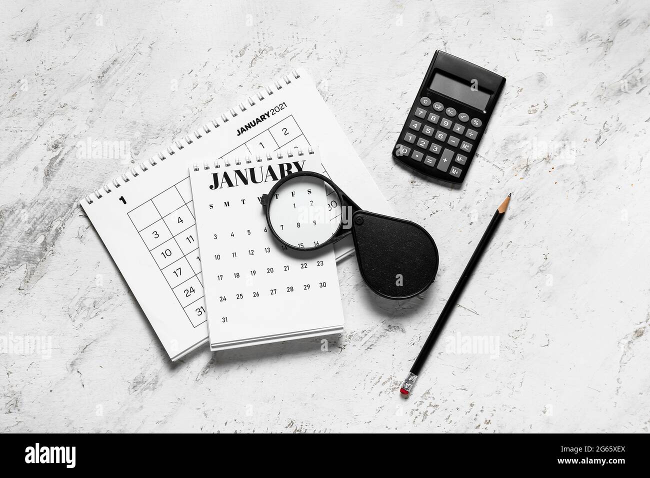 Flip paper calendars, pencil, calculator and magnifier on light ...