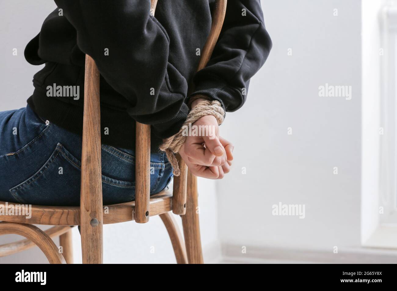 Female hostage with tied hands sitting on chair in room Stock Photo - Alamy