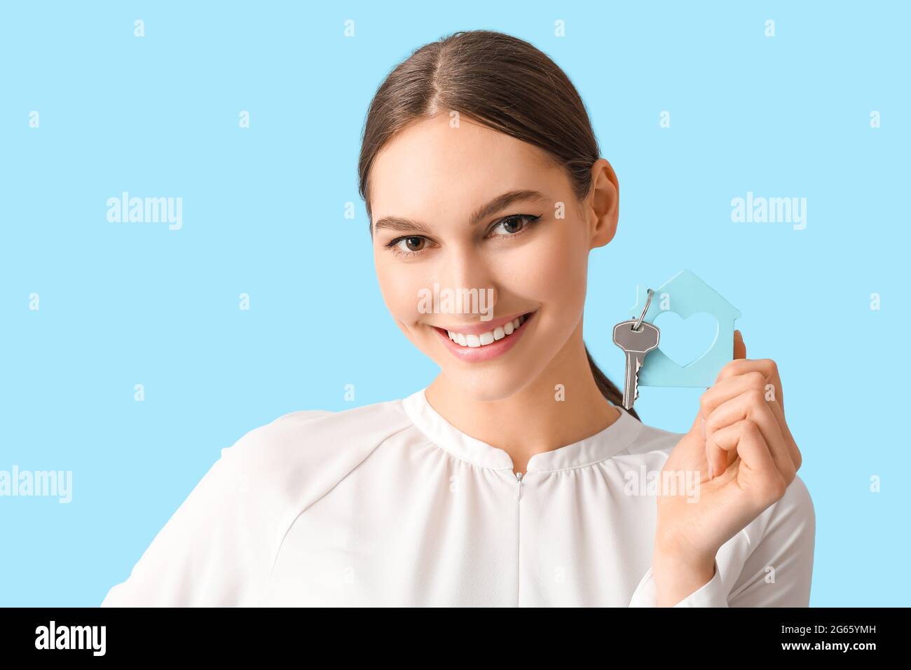 Happy young woman with key from house on color background Stock Photo ...