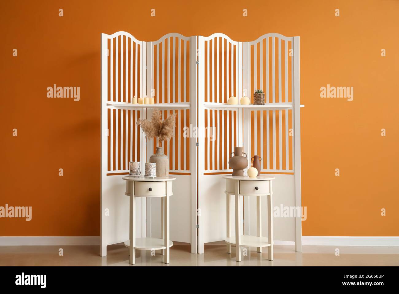 Folding screen and tables with decor near color wall Stock Photo - Alamy