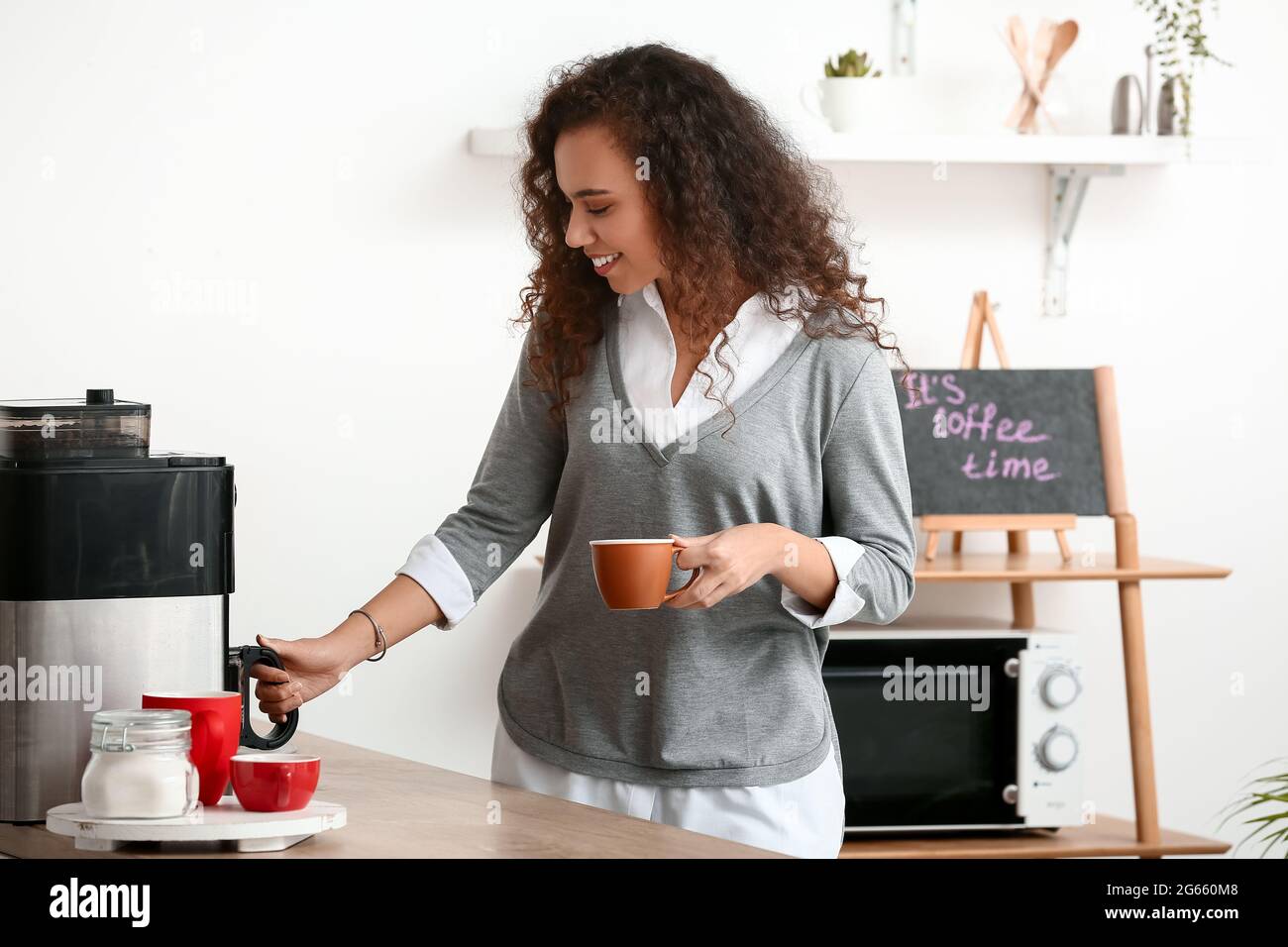 Beautiful young woman making coffee in kitchen Stock Photo - Alamy