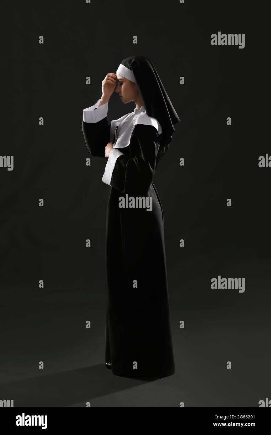 Young praying nun on dark background Stock Photo - Alamy