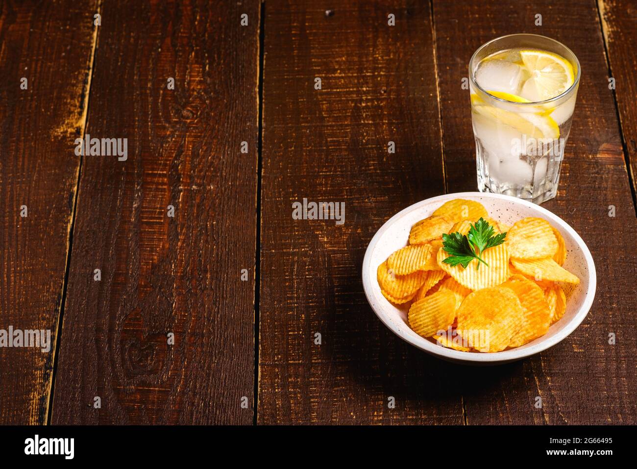 Fresh ice cold water drink with lemon near to fried potato chips with ...