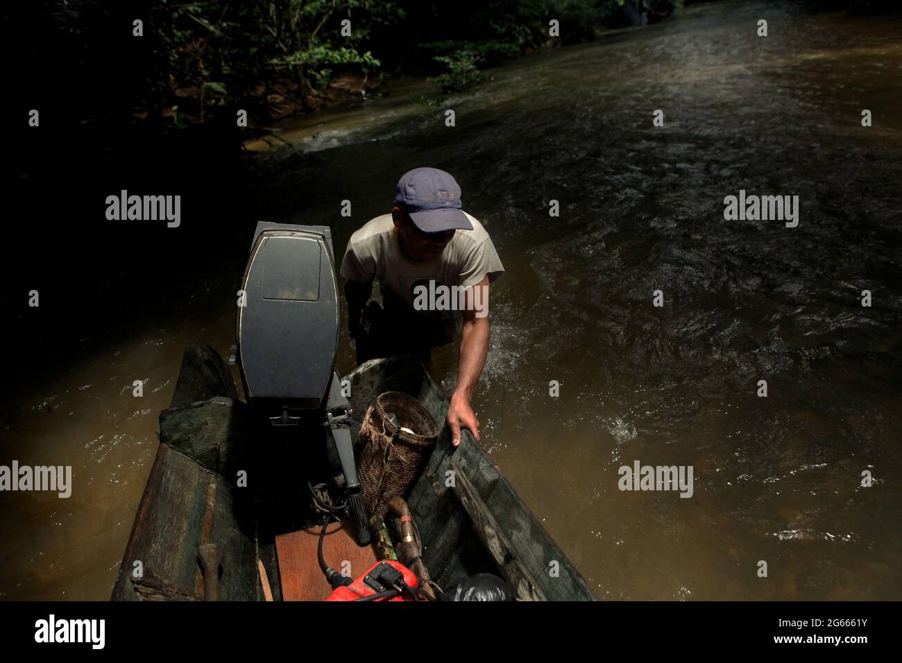 A boat motorist pushing the boat to move on shallow water in the river ...