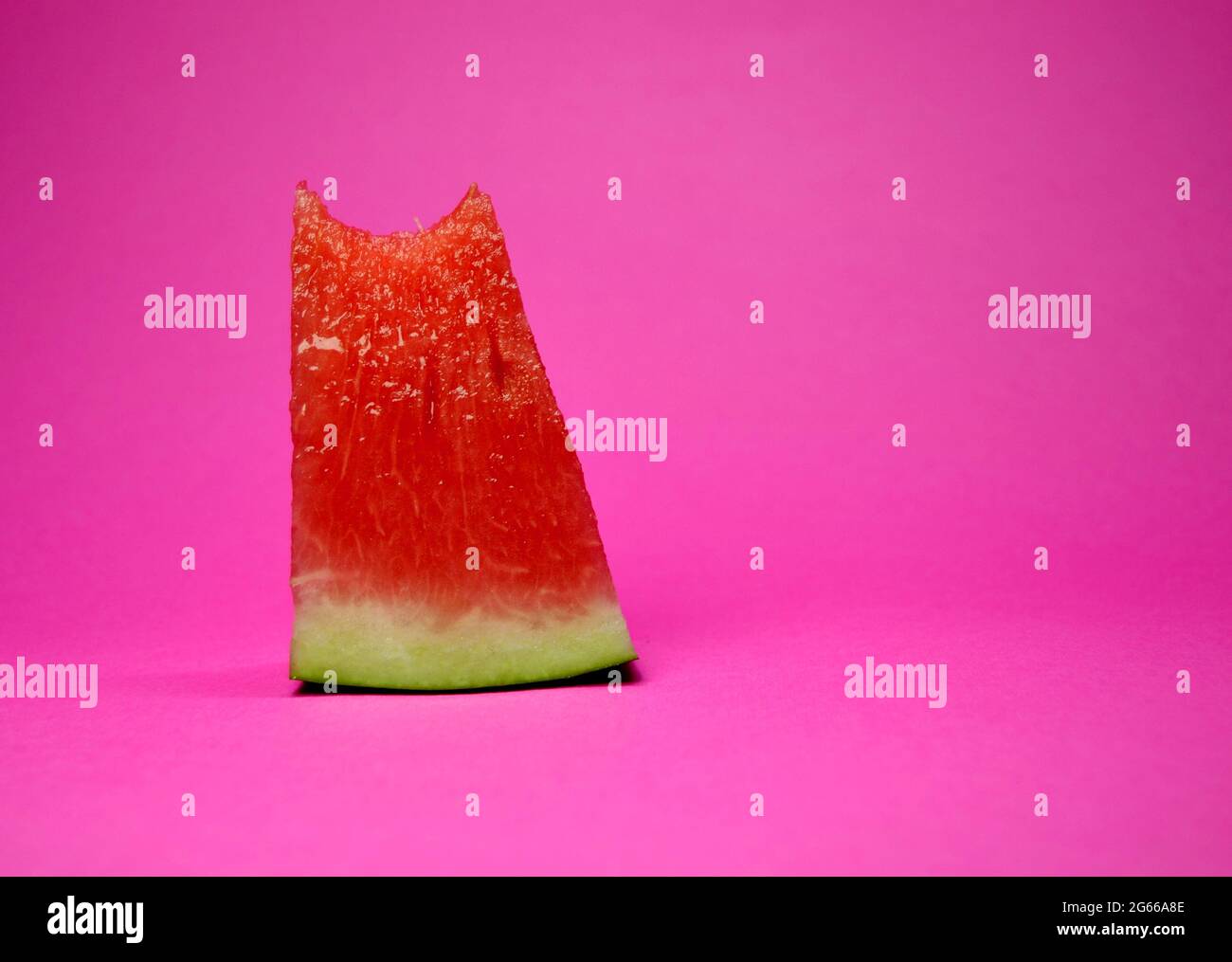 Fresh bitten watermelon slice isolated over pink background. Space for ...