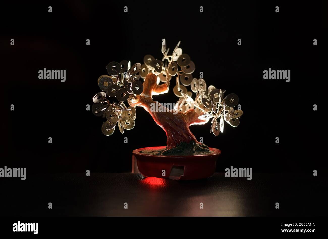 Chinese money tree statuette on a black background illuminated from ...