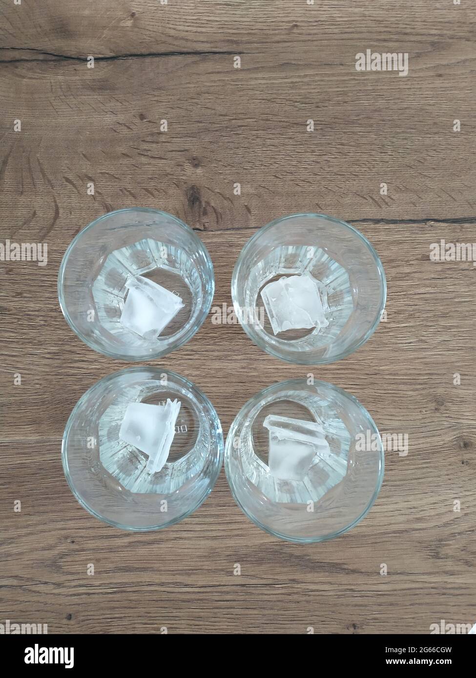 four empty glasses of ice on a wooden table Stock Photo - Alamy