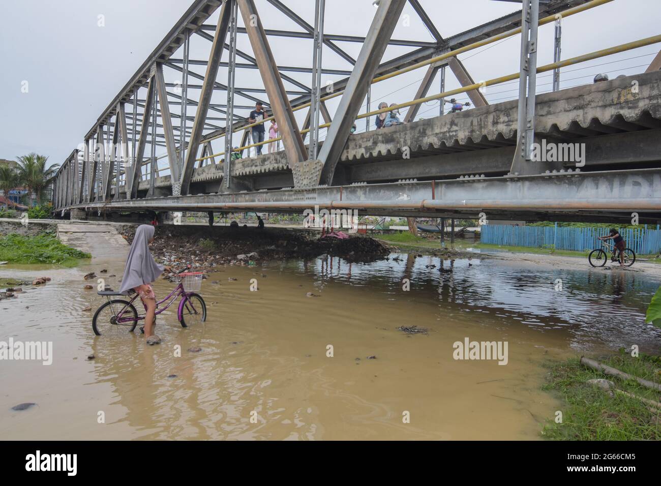 Palu, Indonesia. 03rd July, 2021. A child cycles through a puddle of ...