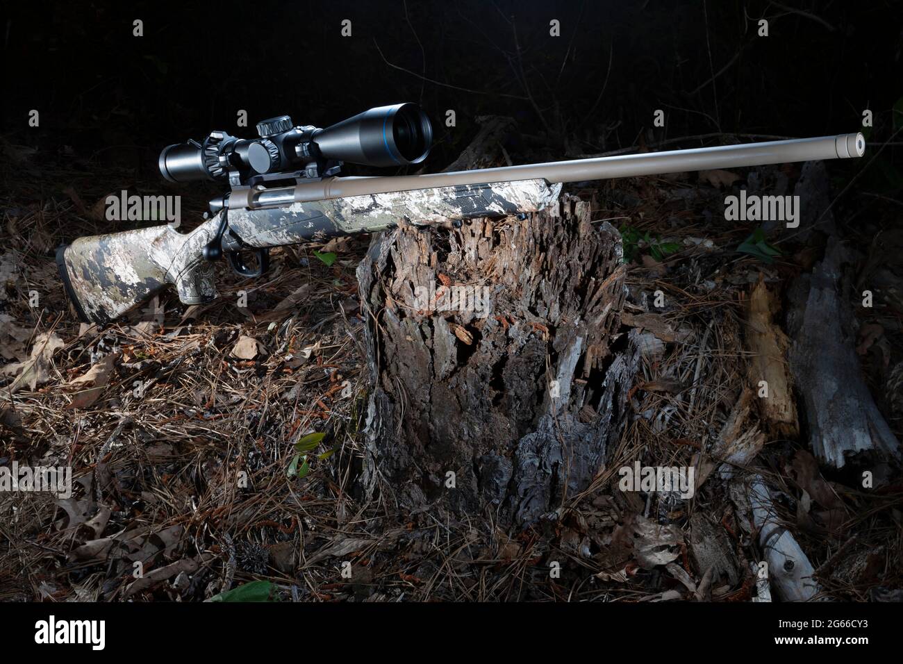 Bolt action rifle with a high powered scope on a tree stump at dusk ...