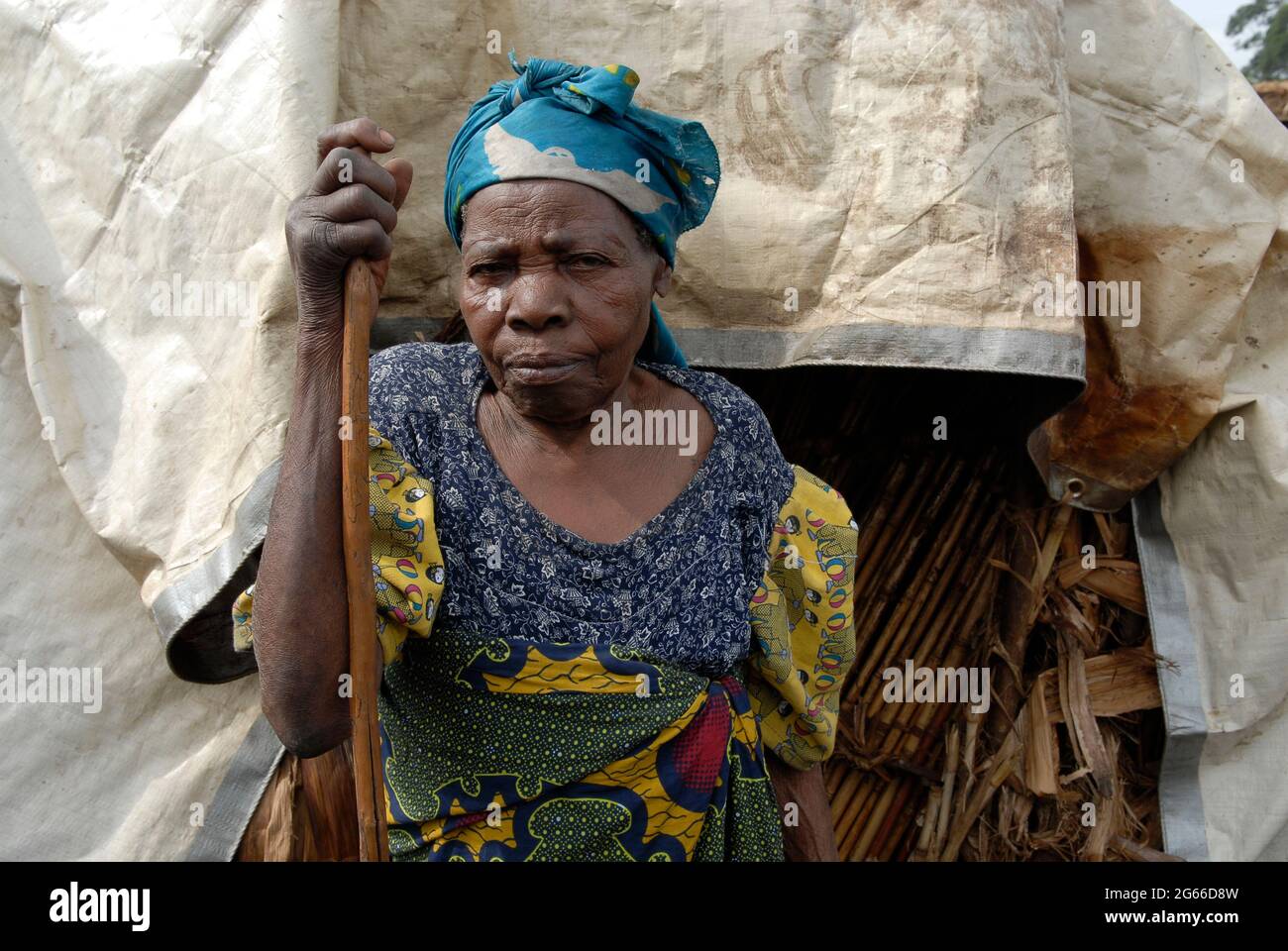 A Congolese displaced woman stands in front of a makeshift straw hut ...
