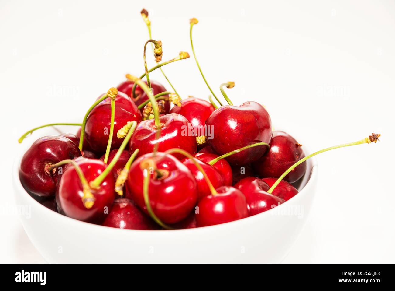 Red cherries inside a white cup on a white background Stock Photo - Alamy