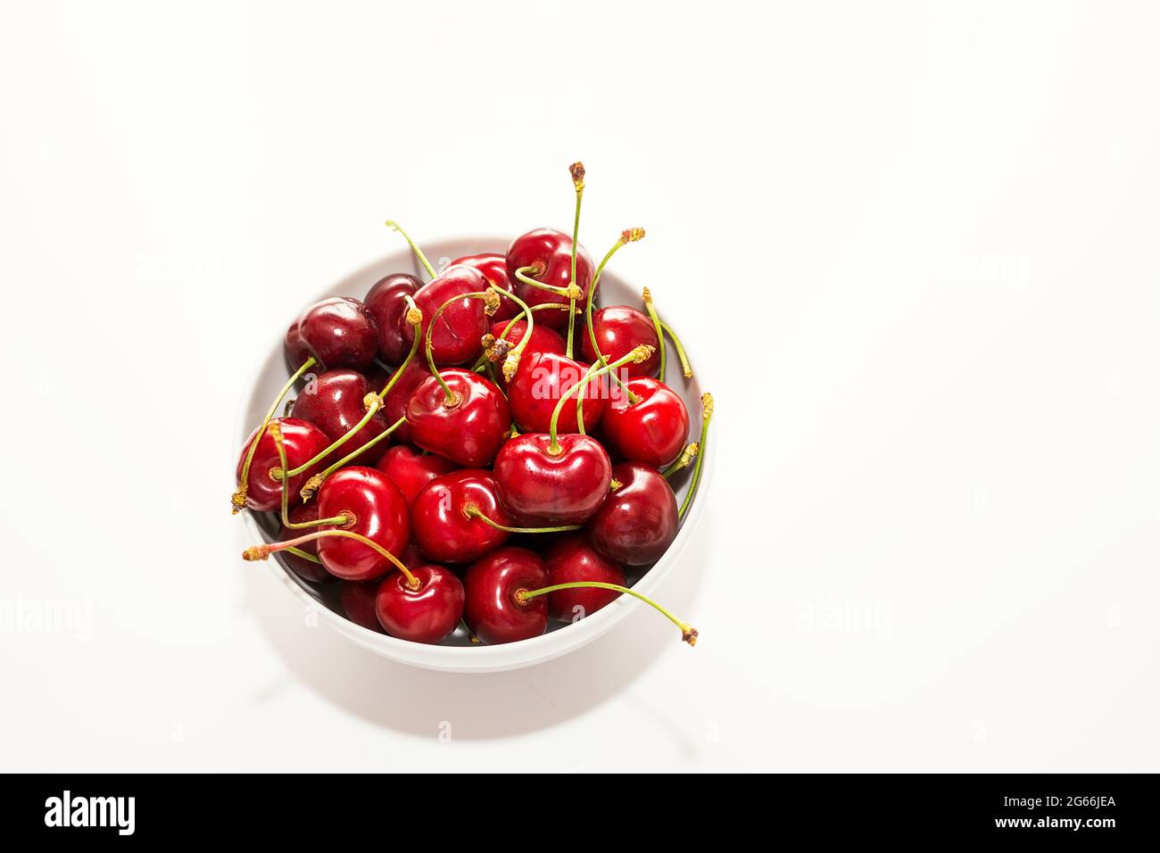 Red cherries inside a white cup on a white background Stock Photo - Alamy