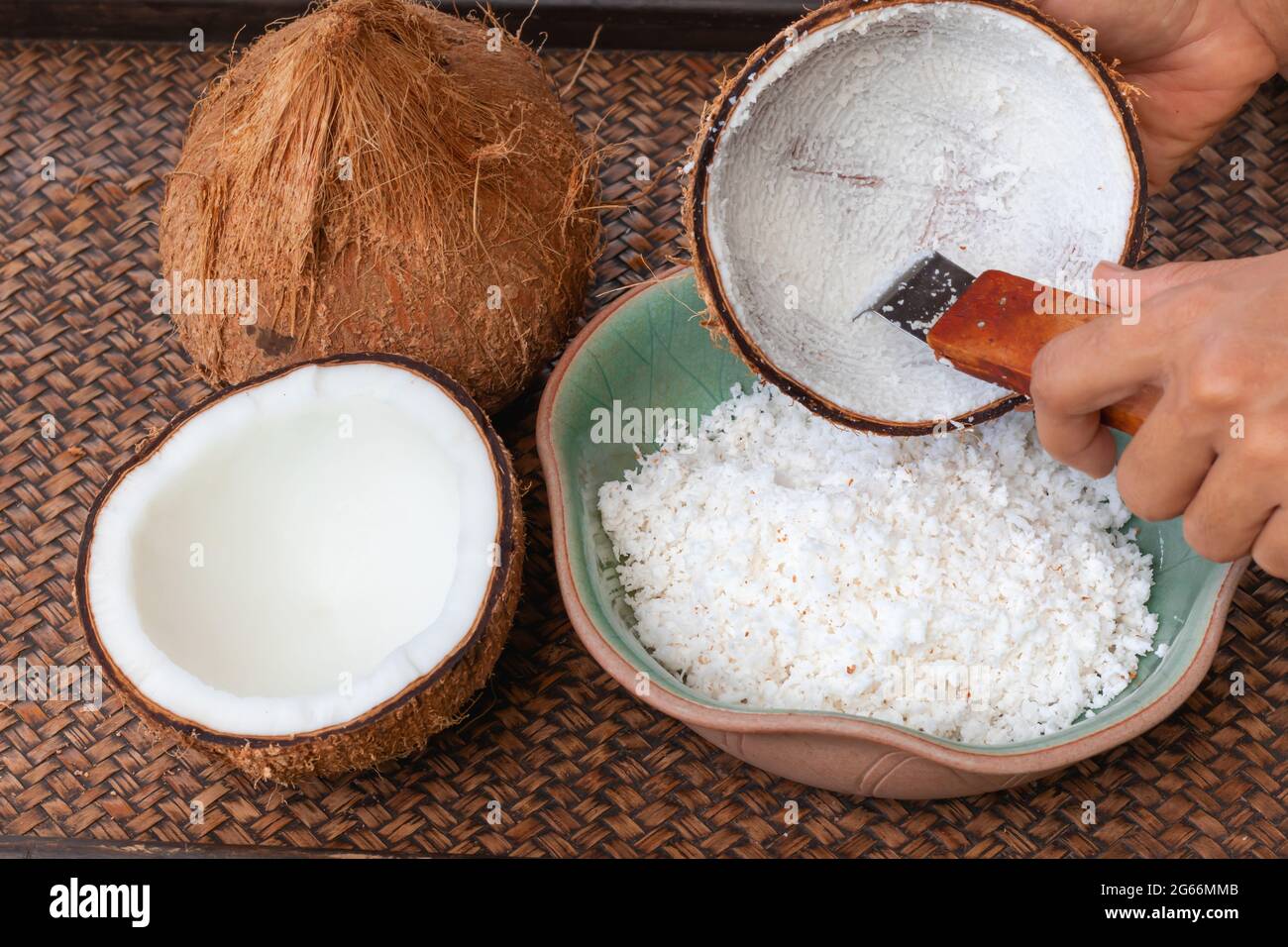 Coconut grating by hand and there is a whole coconut beside it. On dark ...