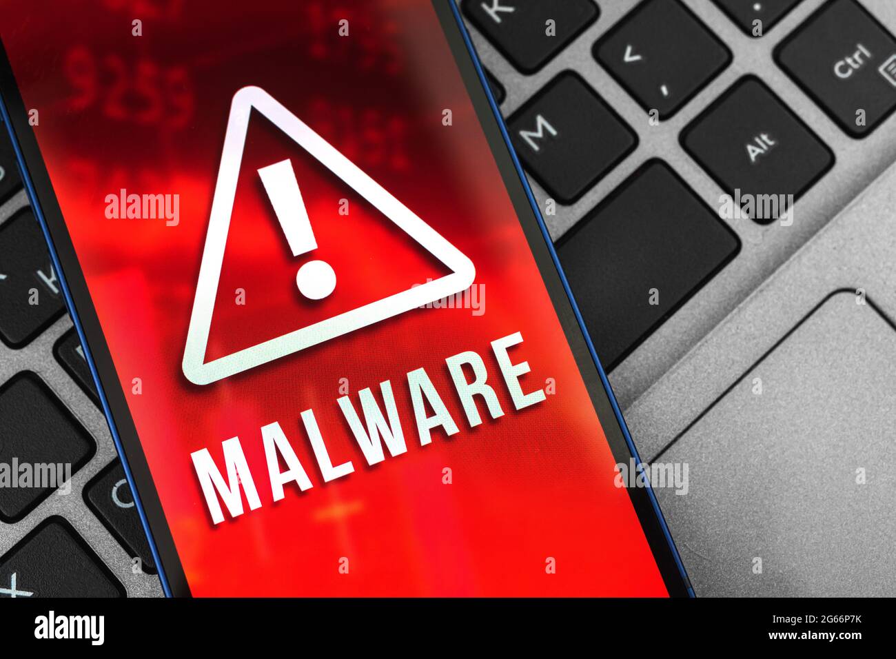 Mobile phone with malware sign on the screen, background of laptop ...